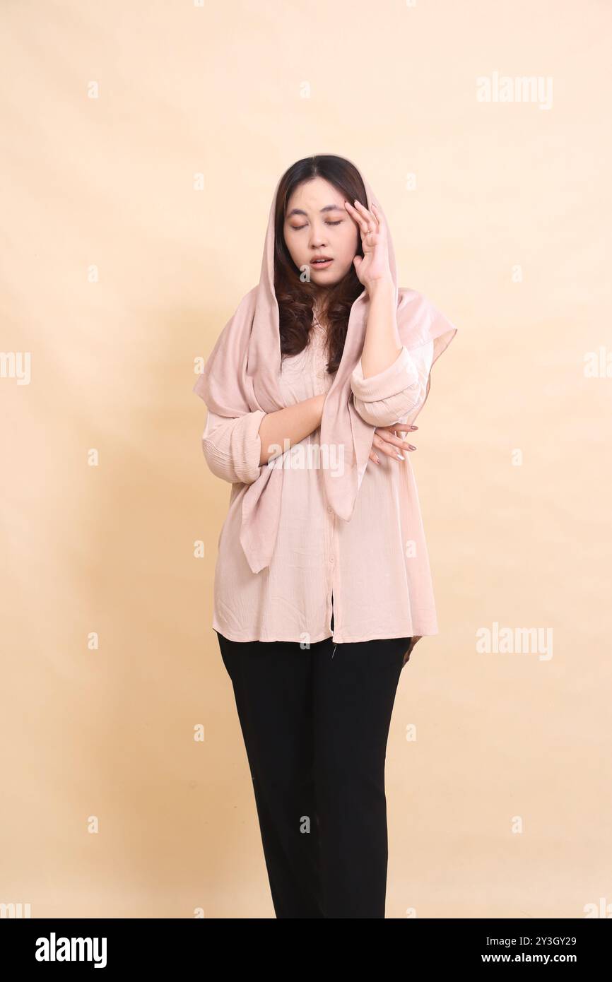 Asian adult woman semi-hijab standing candid dizzy headache arms ...