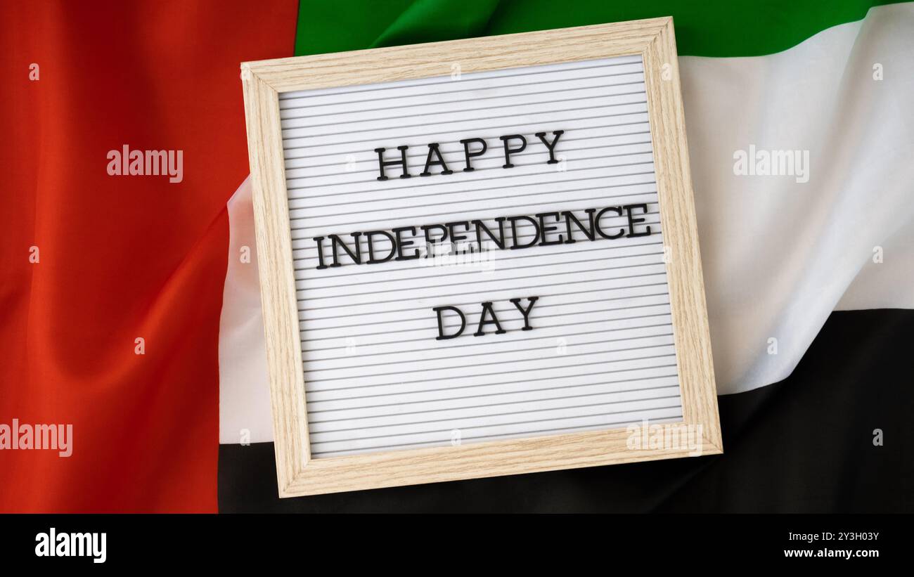Text HAPPY INDEPENDENCE DAY on background waving flag of UAE. National ...