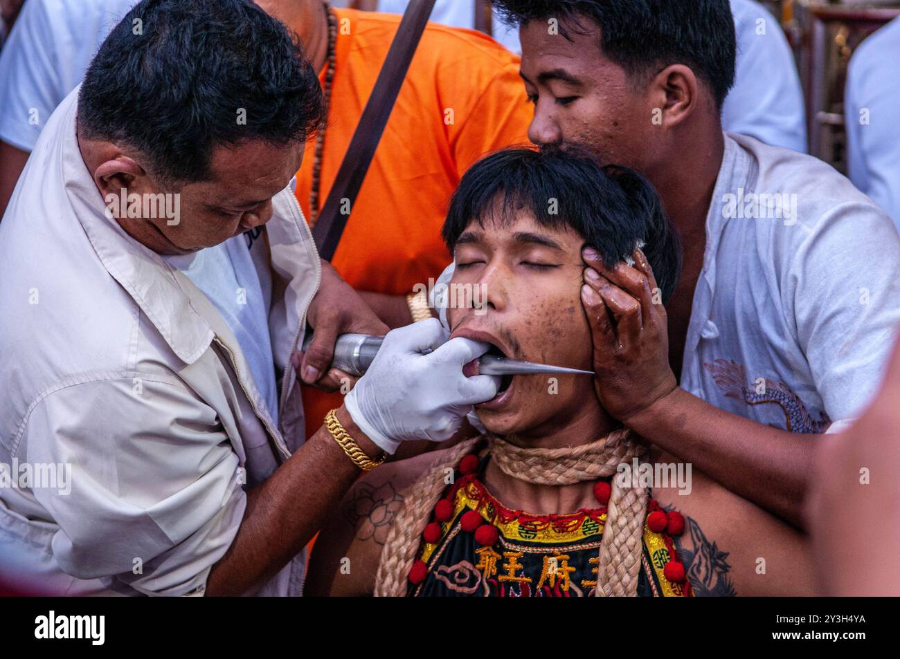 Ma-Thong (spirit medium) getting cheek pierced with piercing gauge ...