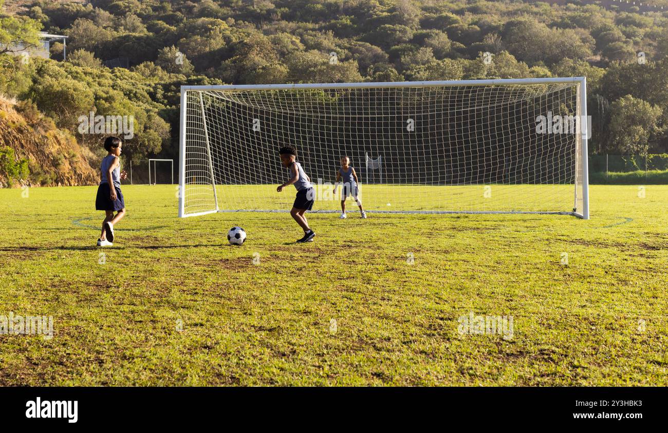 Outdoors, playing soccer on school field, multiracial boys practicing ...