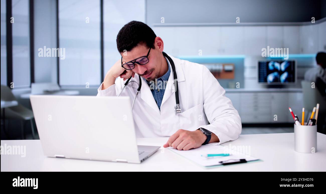 Tired Young Male Doctor Resting At Computer Desk In Hospital Stock ...