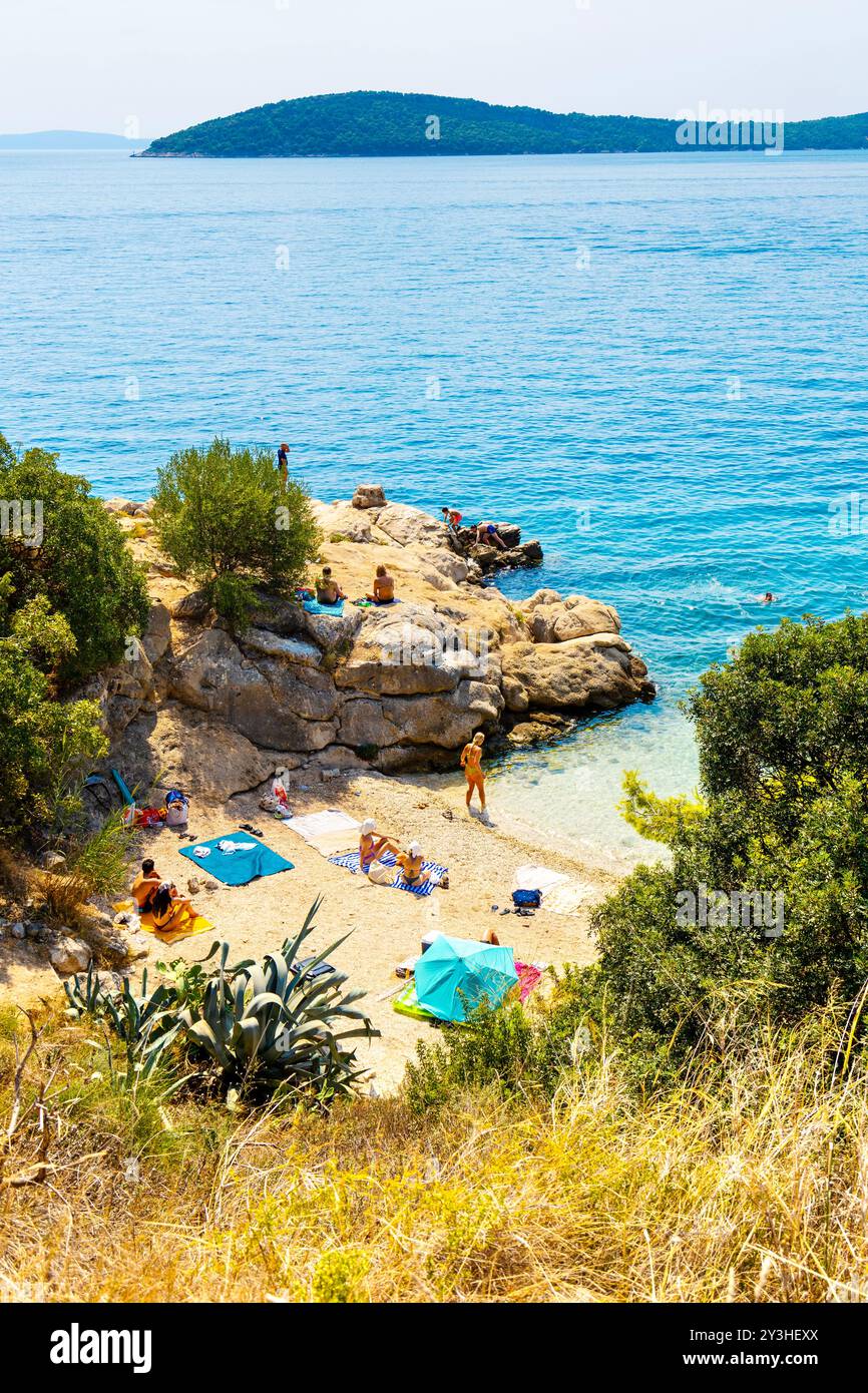 People swimming and sunbathing in a small cove by Kasjuni Beach (Plaža ...