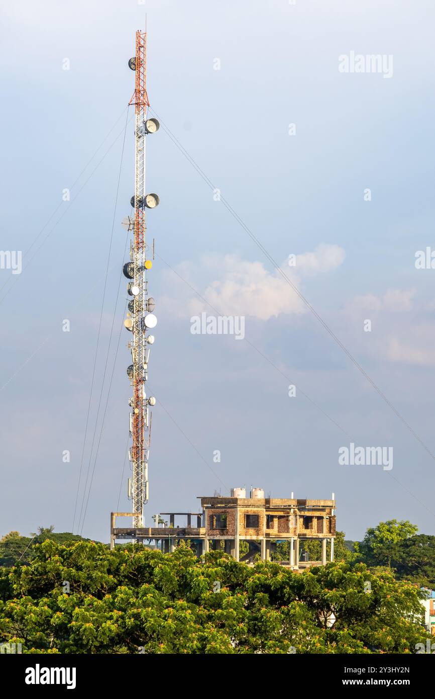 Mobile network telecommunication tower antenna on red and white communication tower against blue ...