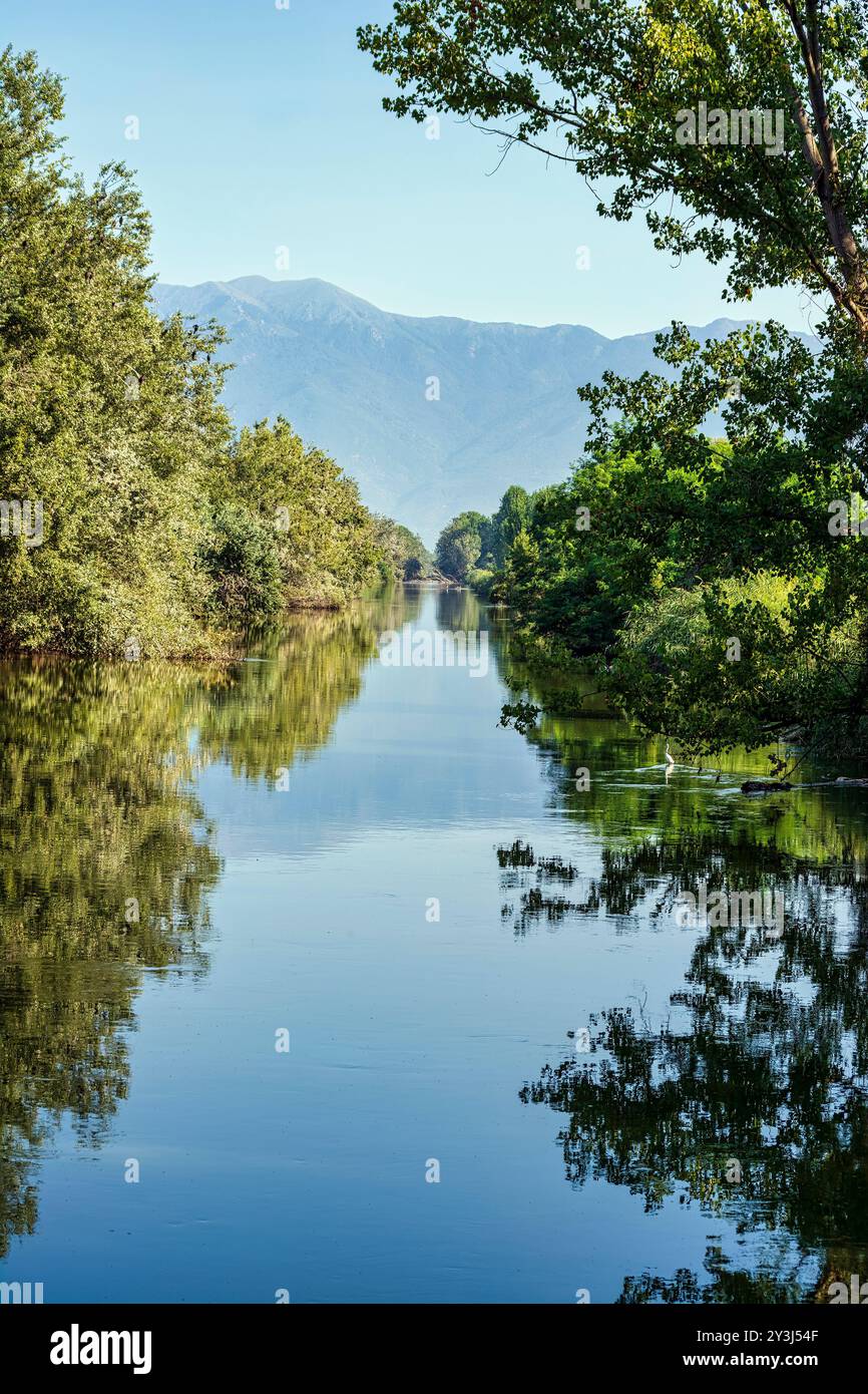 A calm river at Lake Kerkini, Greece, reflecting the surrounding trees ...