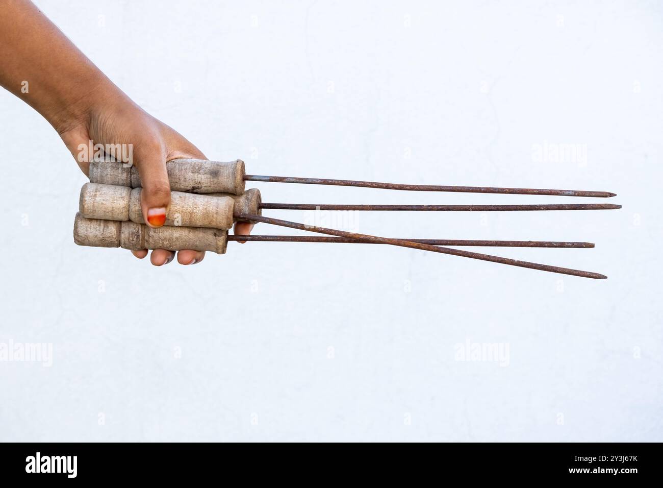 Female hand holding many rusted metal skewers with wooden handle on ...