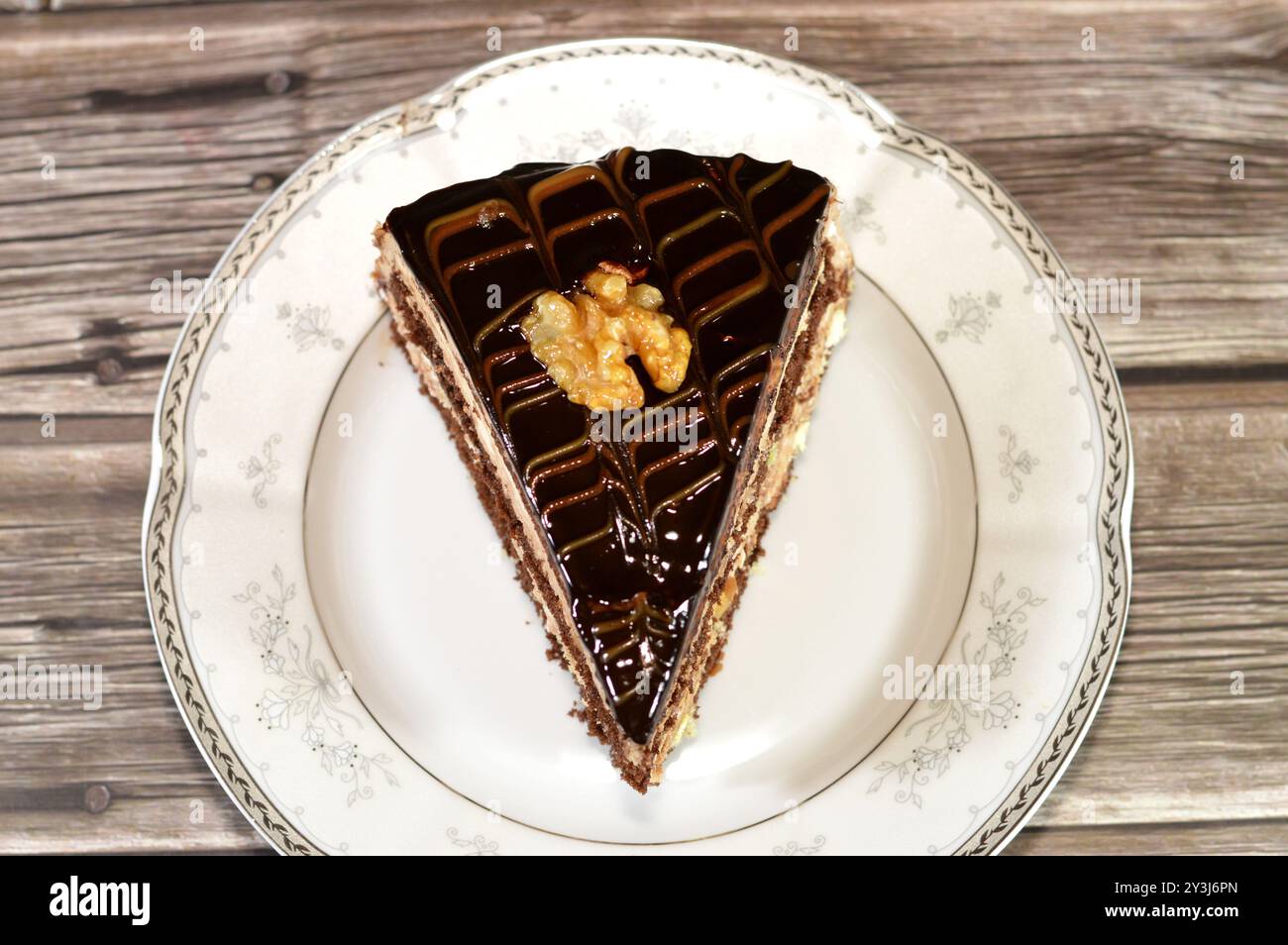 chocolate triangular spongy cake piece filled and topped with walnut ...