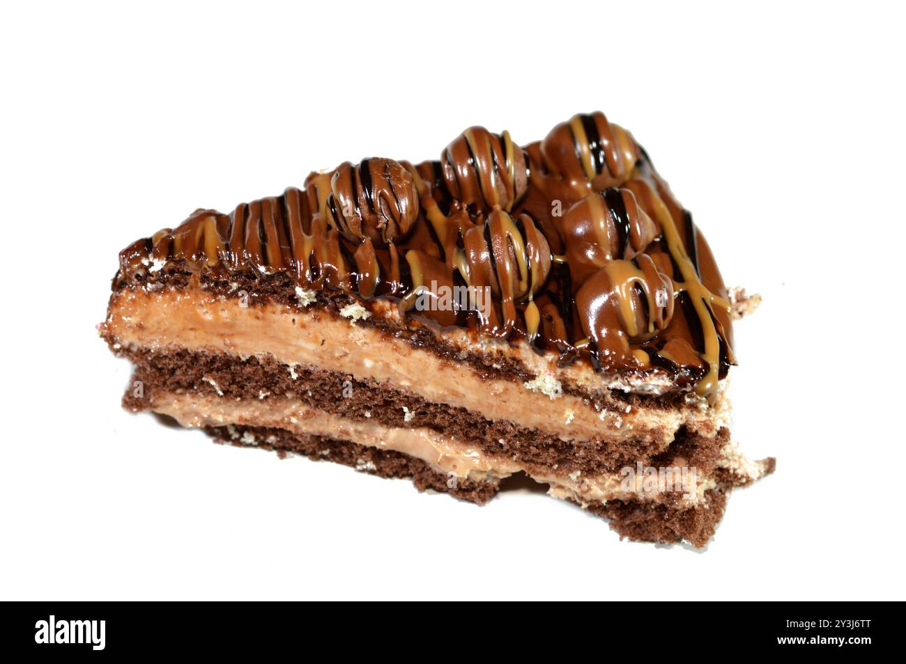 A chocolate triangular spongy cake piece filled and topped with layers ...