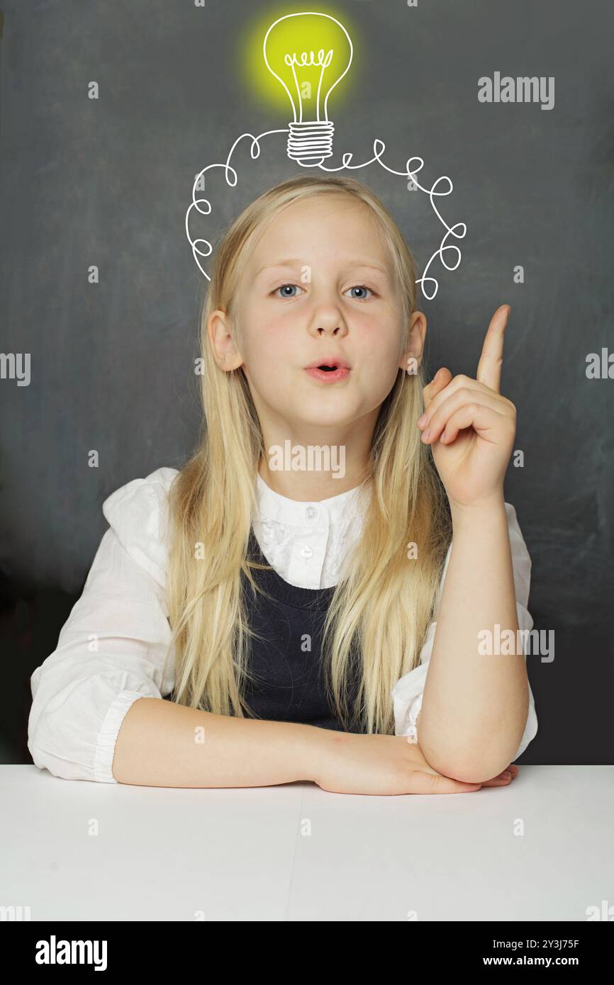 Curious child girl student with yellow light bulb on school blackboard ...