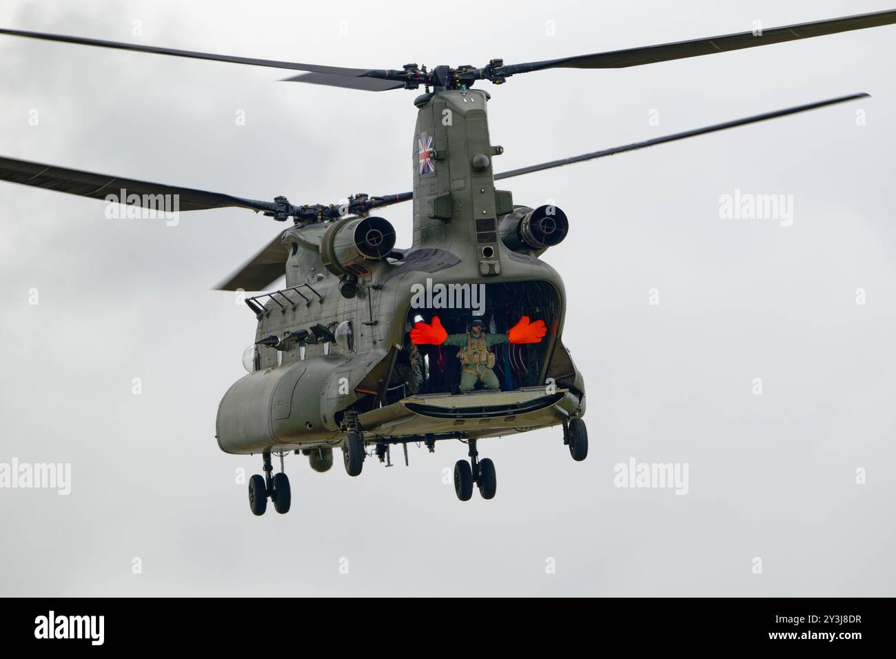RAF Helicopter Loadmaster wearing big orange gloves waves out of the ...