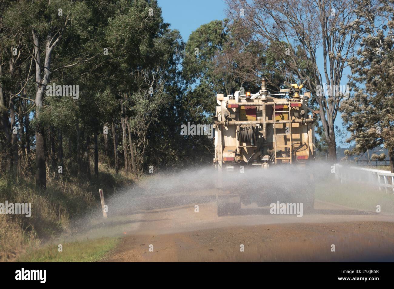 Water tanker spraying fine mist over dry and dusty unsealed road in ...