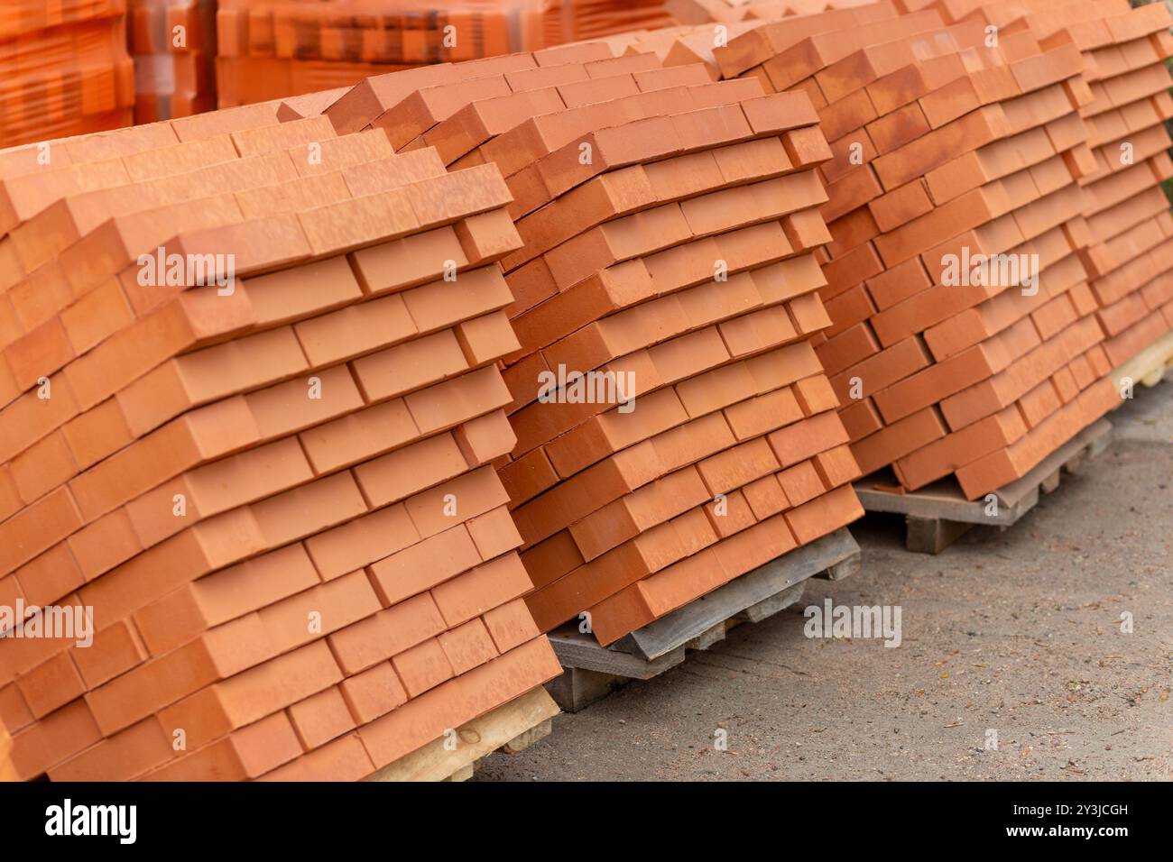 Stacks of new, red ceramic brick stacked on wooden pallets. Lots of new ...