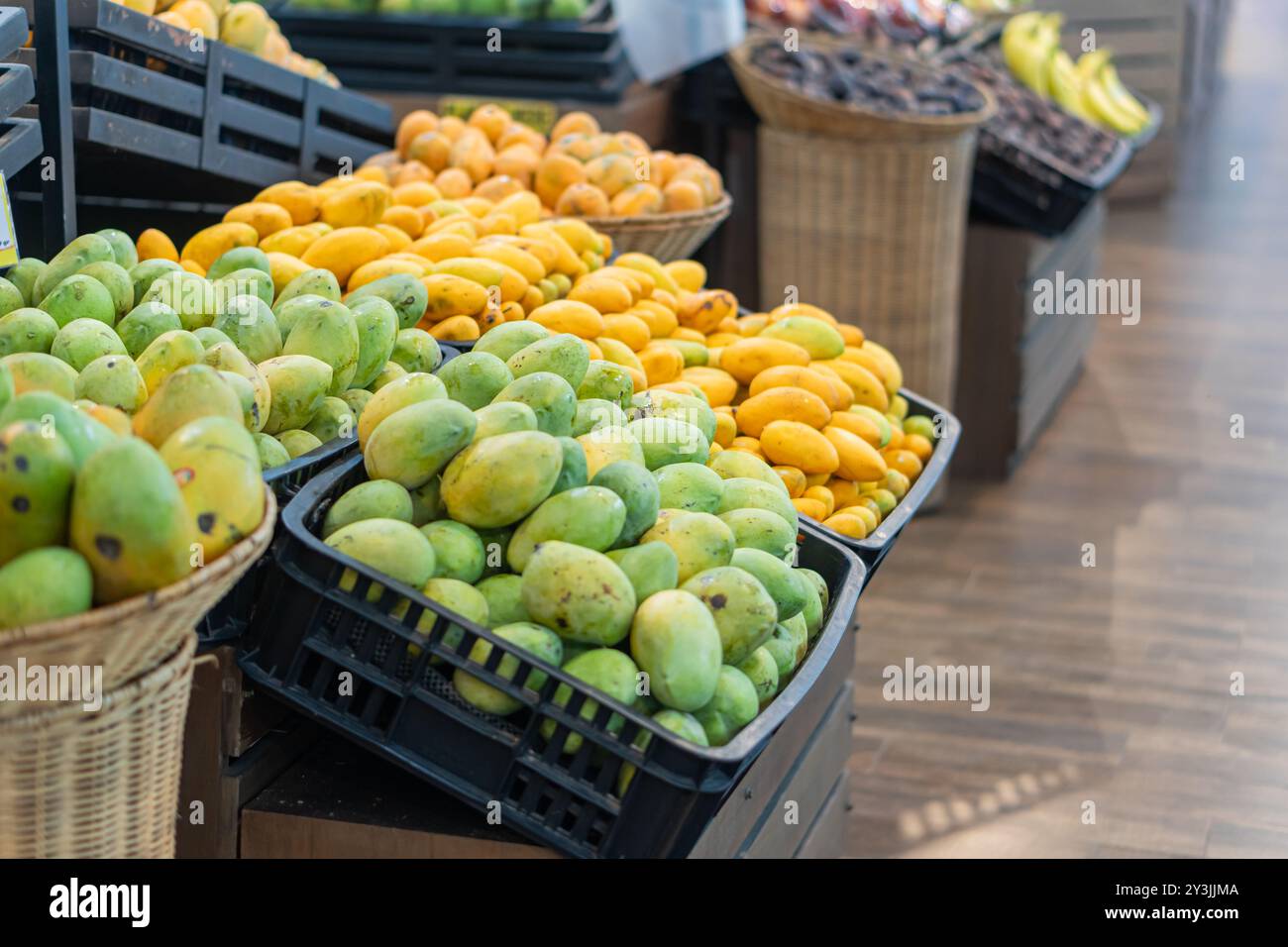 A basket filled with ripe mangoes in various shades of green and yellow ...
