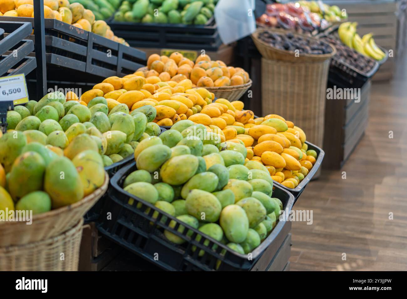 A basket filled with ripe mangoes in various shades of green and yellow ...