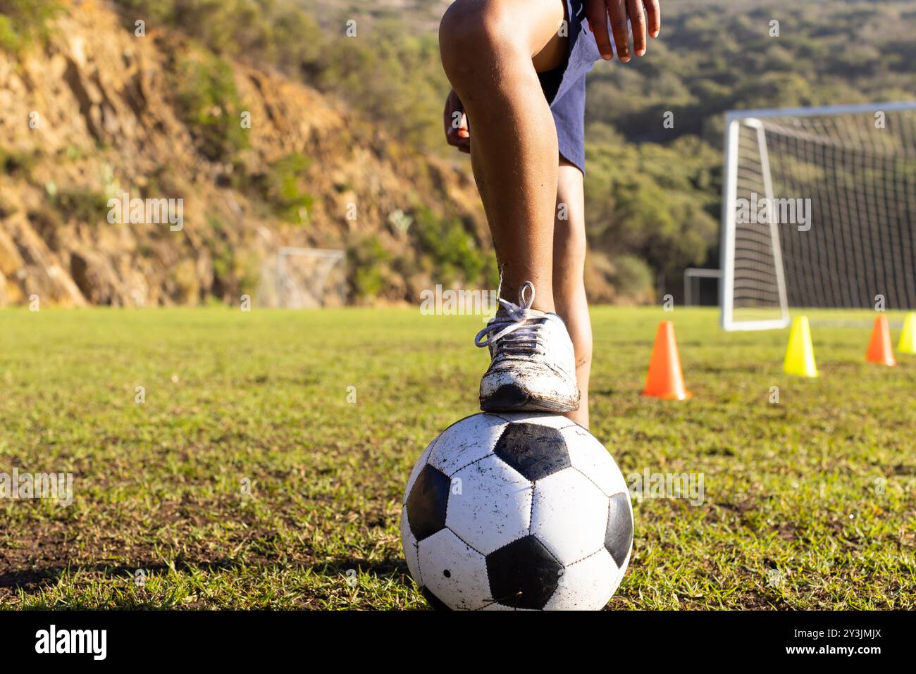 Outdoors, playing soccer on field, boy balancing foot on soccer ball ...