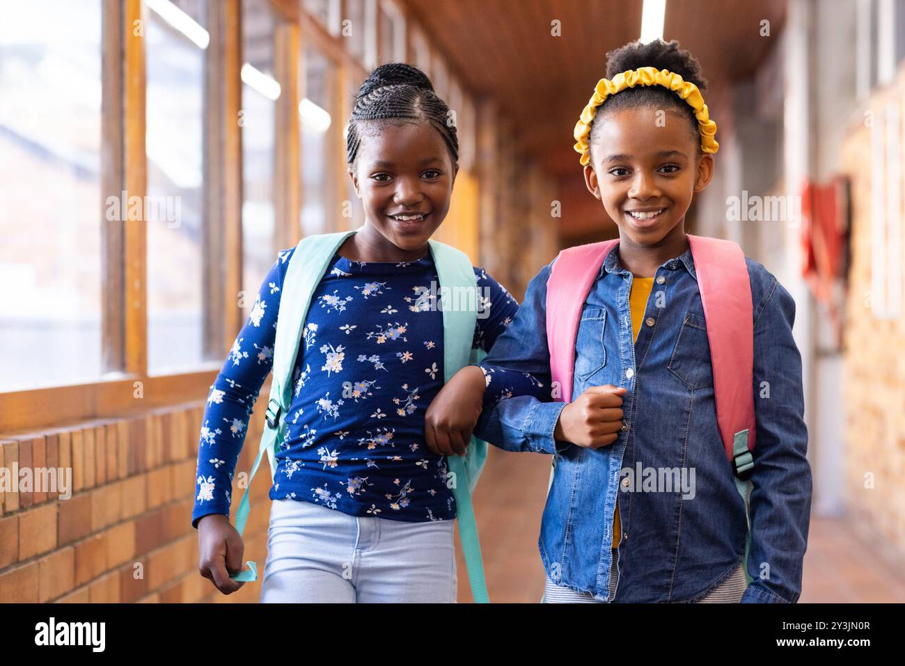 Walking in school hallway, two african american girls with backpacks ...