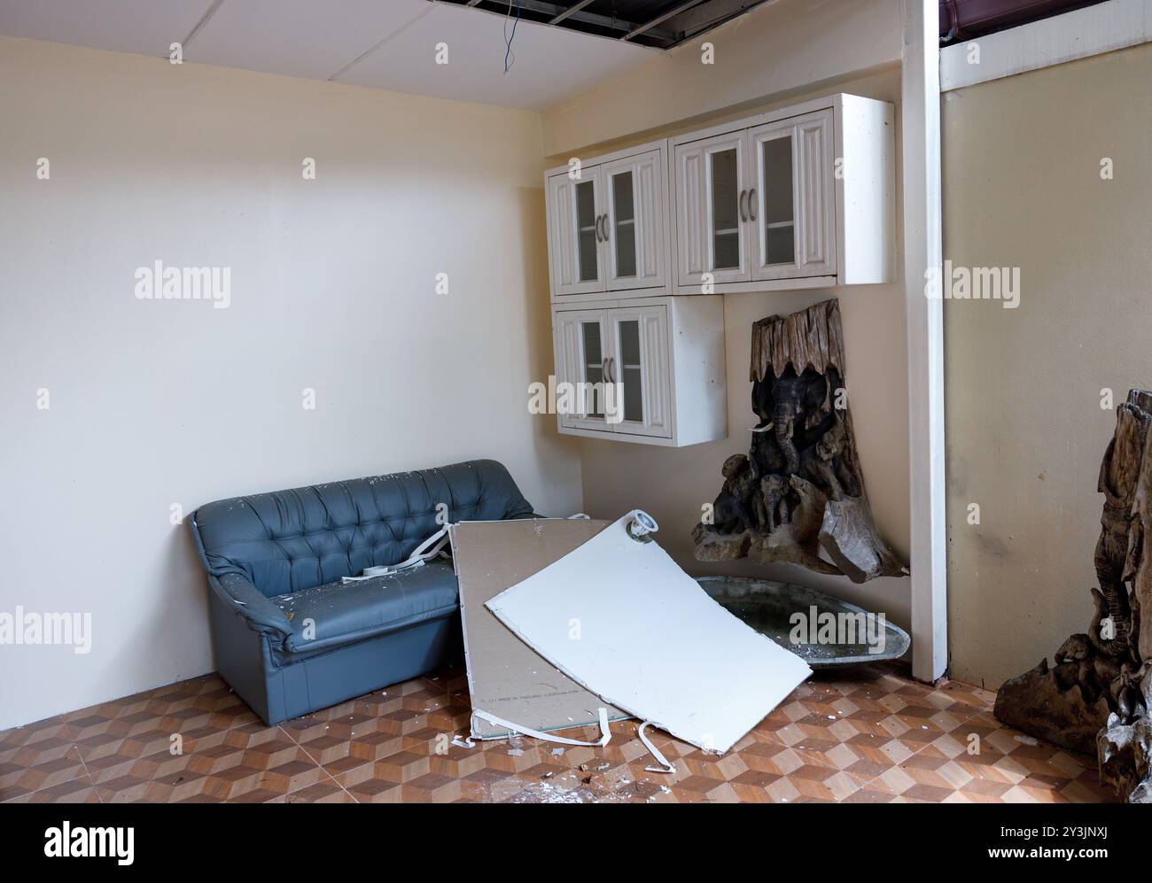 A damaged room with a broken section of ceiling and debris scattered on ...