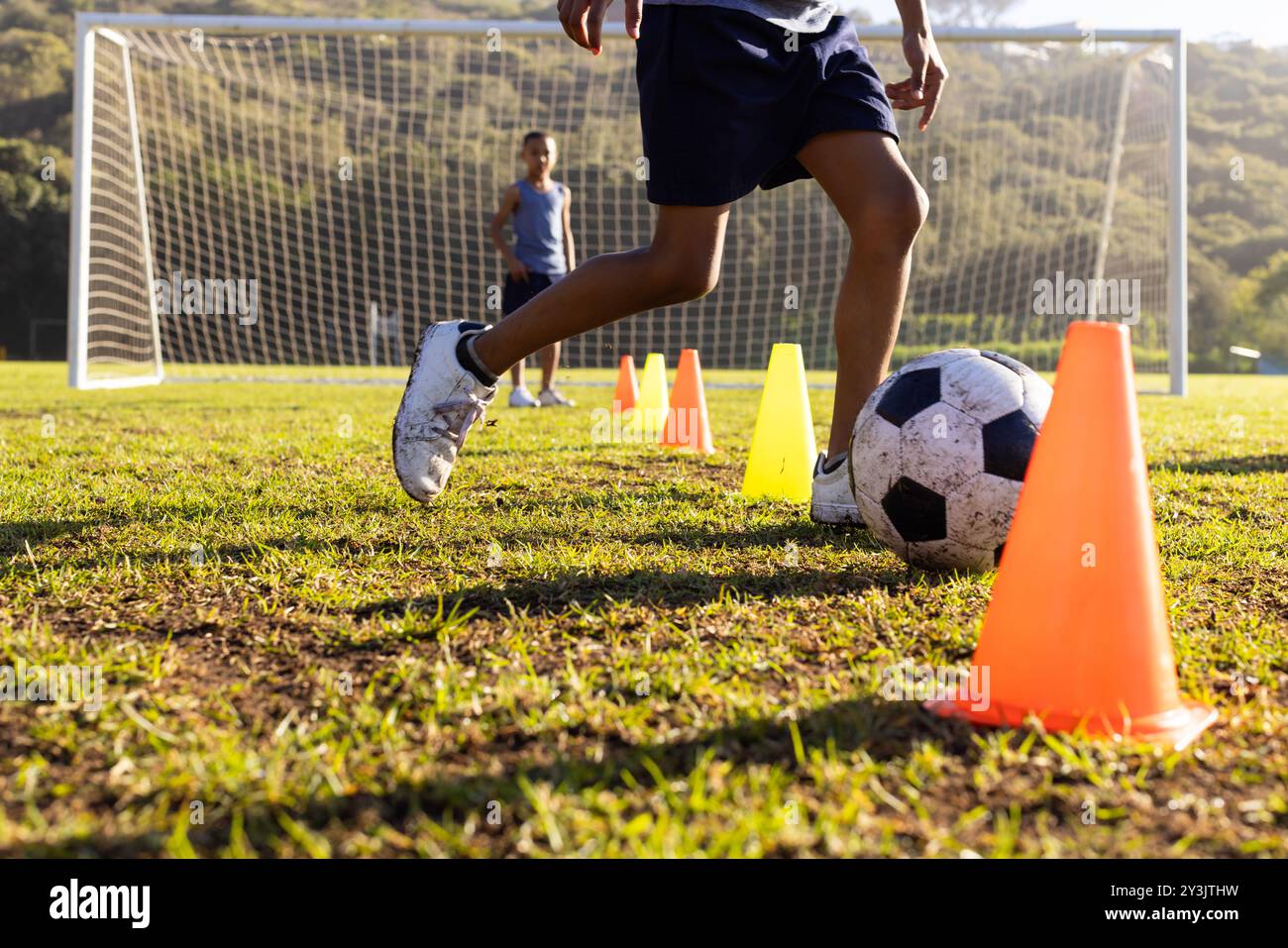 Outdoors, dribbling soccer ball through cones, multiracial boys ...