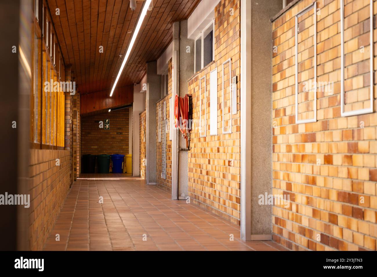 Empty school hallway with brick walls and fire extinguishers, leading ...