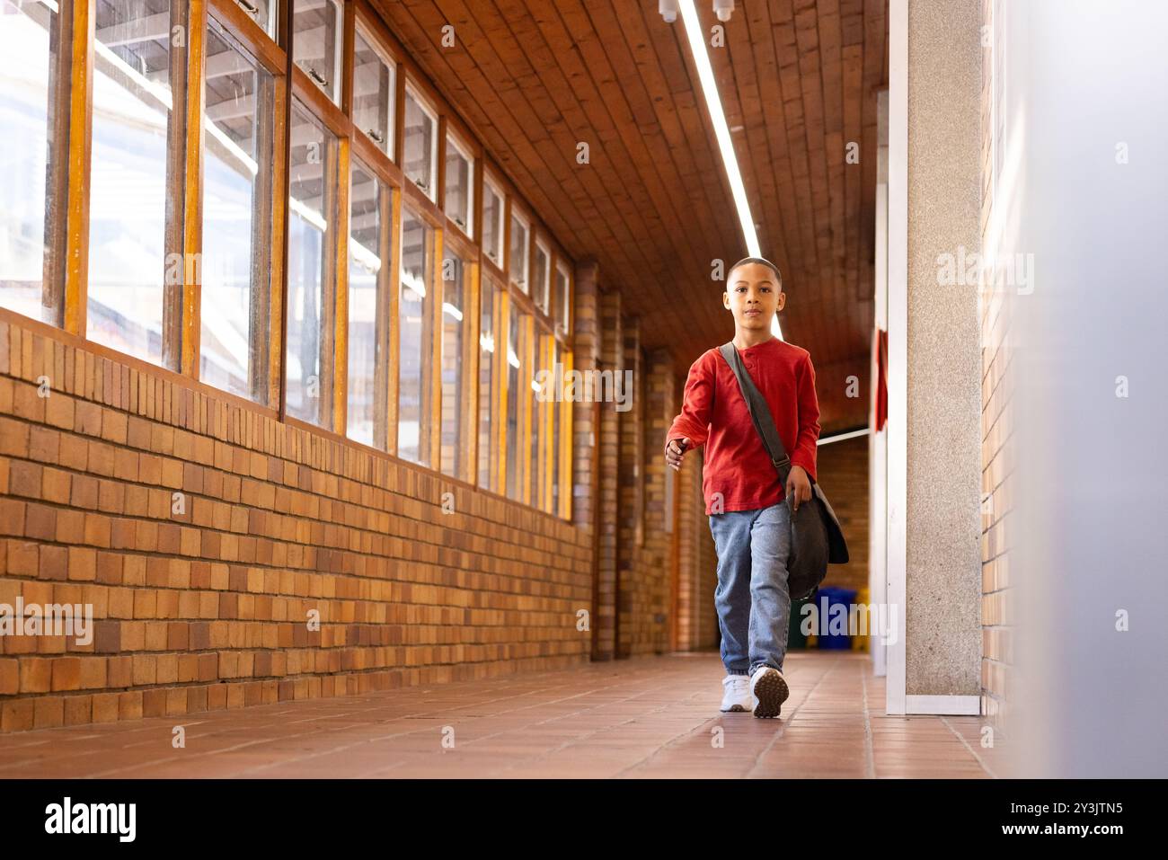 Walking in school hallway, boy carrying bag and wearing red shirt Stock ...