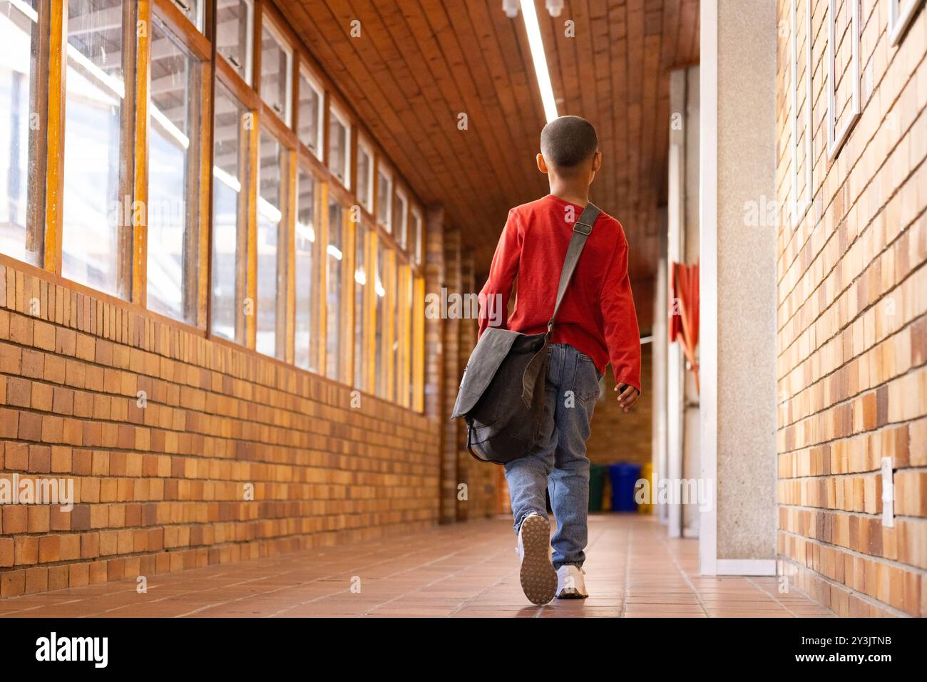 Walking down school hallway, boy with backpack heading to classroom ...