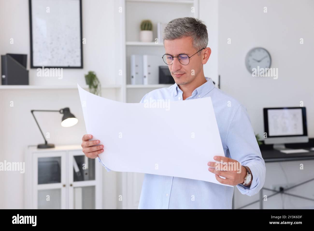 Architect holding paper sheet with engineering drawing in office Stock ...