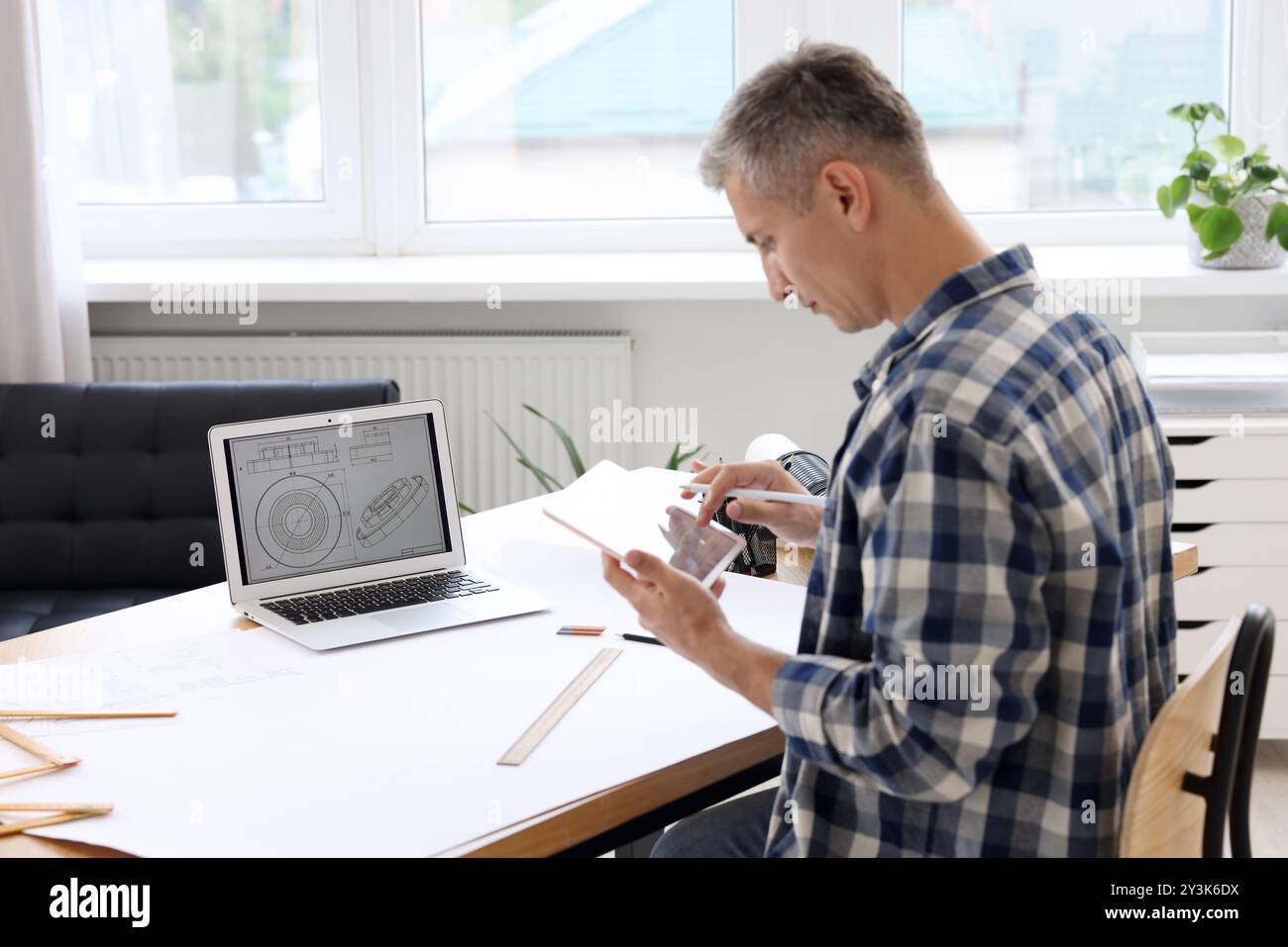 Architect making digital engineering drawing on tablet at table in ...