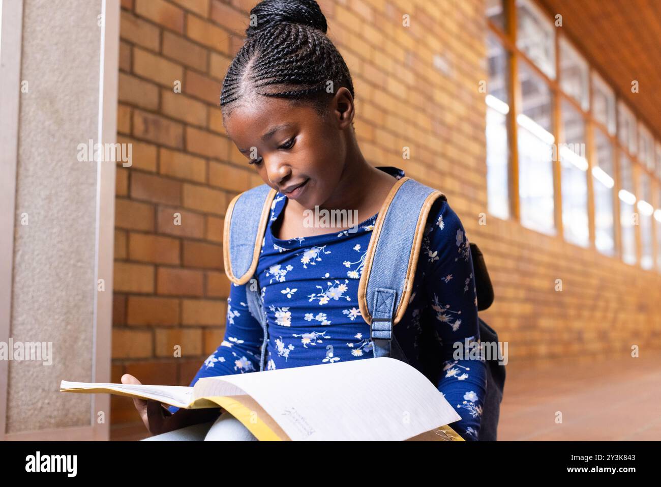 In school, african american girl with backpack reading notebook in ...