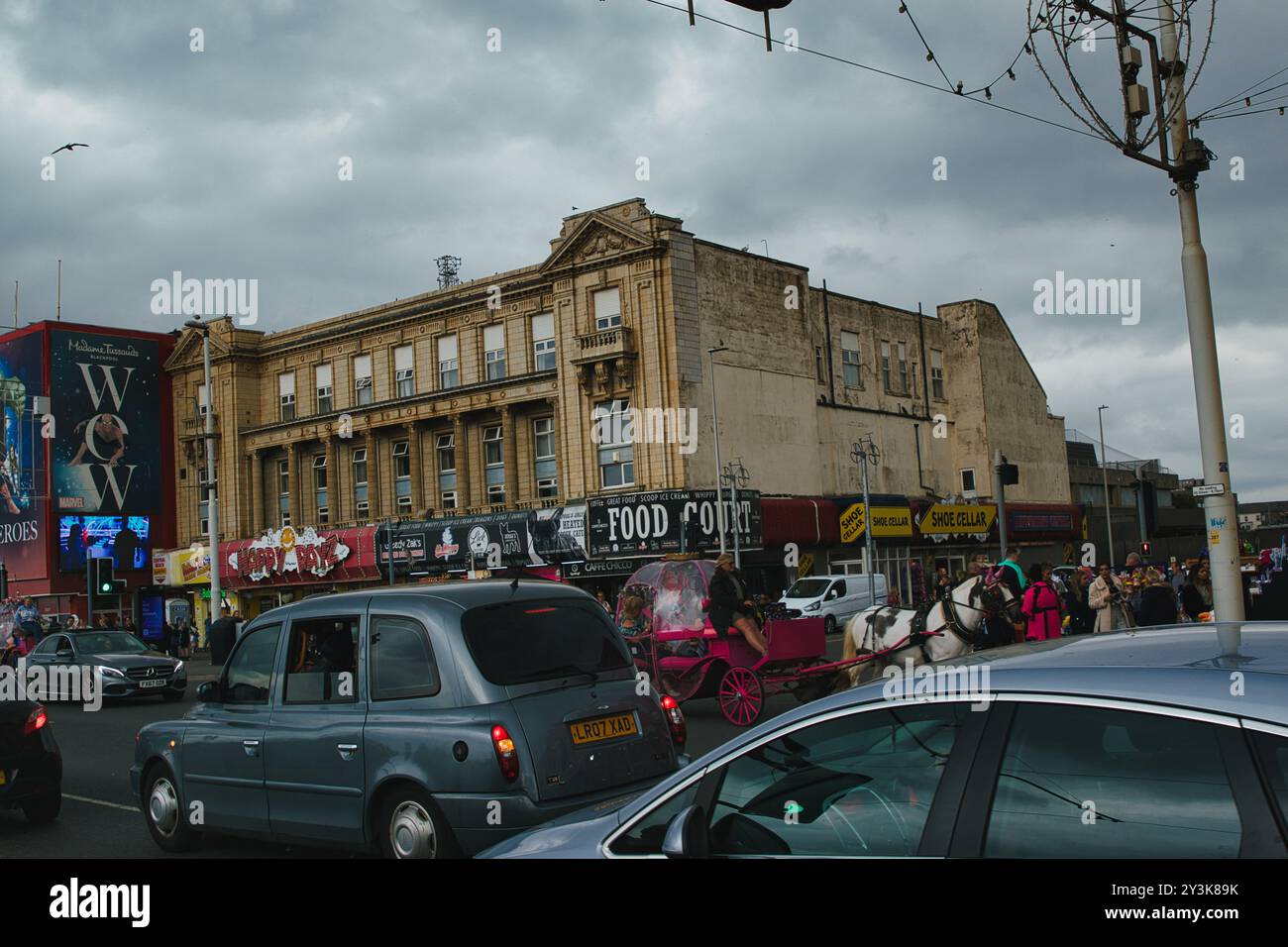 A busy street scene featuring a historic building with a faded facade ...
