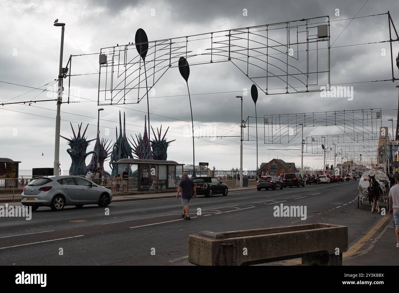 A coastal street scene with a cloudy sky, featuring large artistic ...