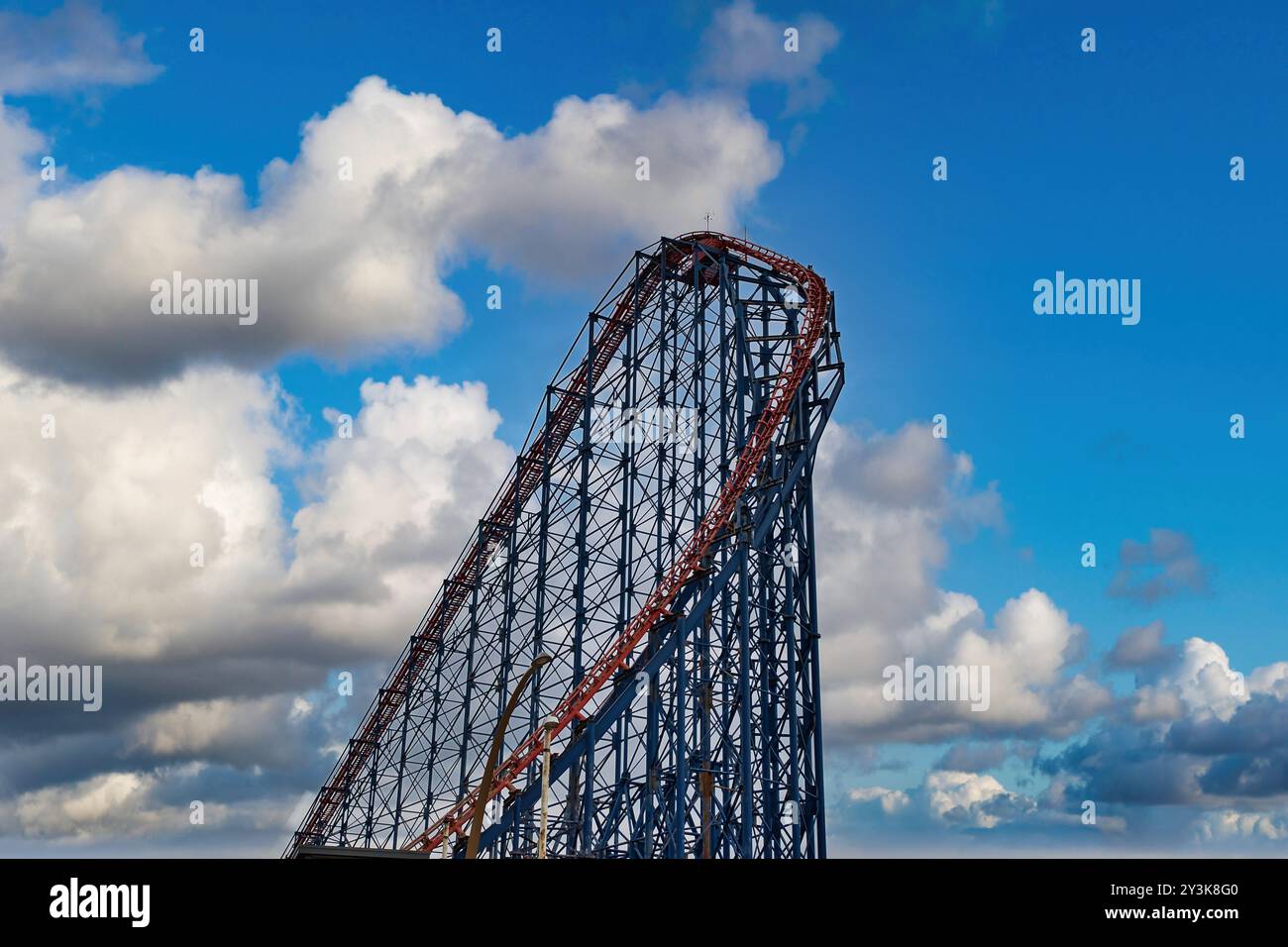 A towering roller coaster reaching its peak against a backdrop of blue ...