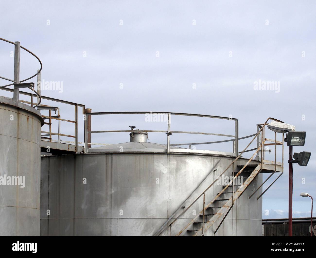 The top of large old silver steel industrial storage tanks with control ...