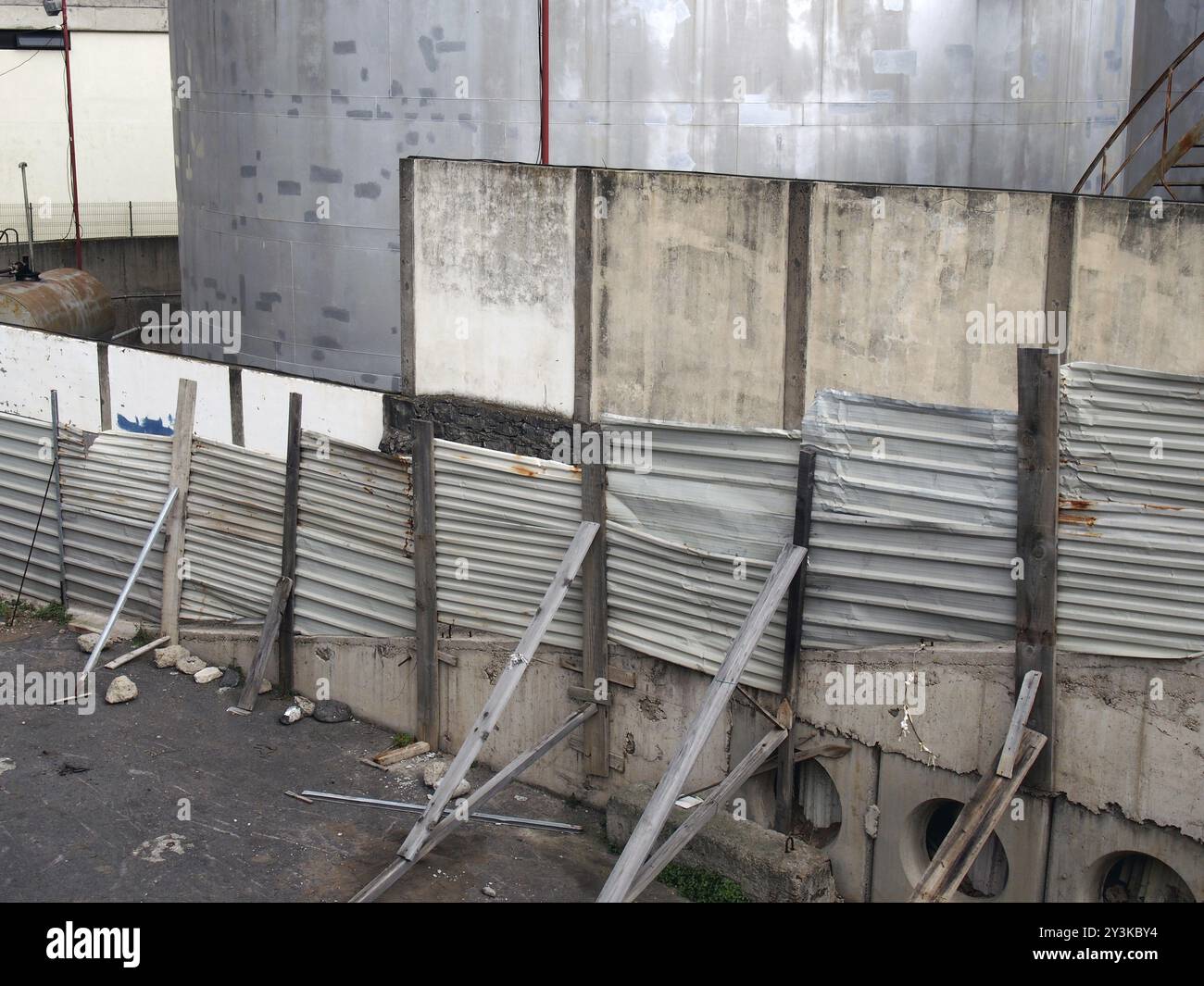 A shabby unsafe fence propped up with pieces of wood and corrugated ...