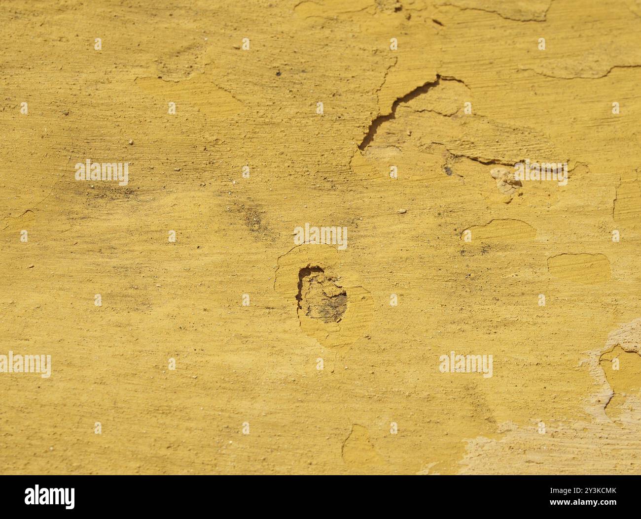 A rough old plaster wall with cracks and dirt with layers of yellow ...
