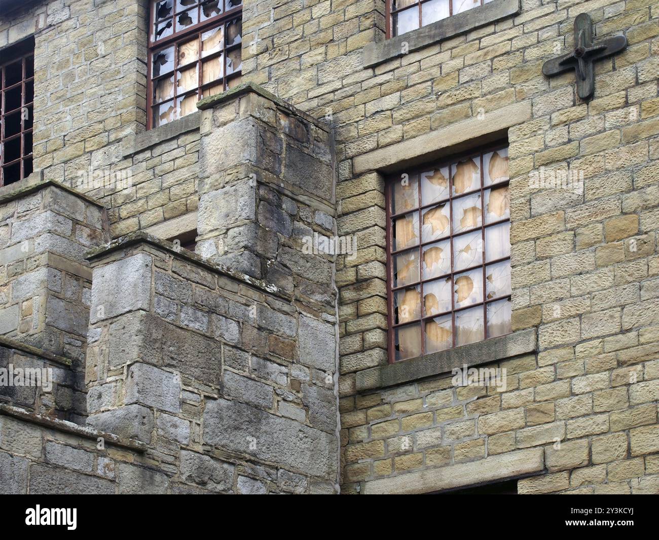 An old abandoned factory building with boarded up and broken windows ...