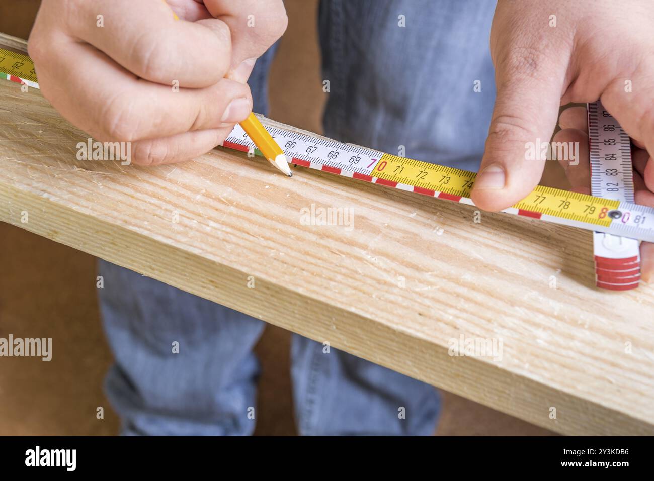 Carpenter is measuring a wooden plank with a measuring tape and making ...
