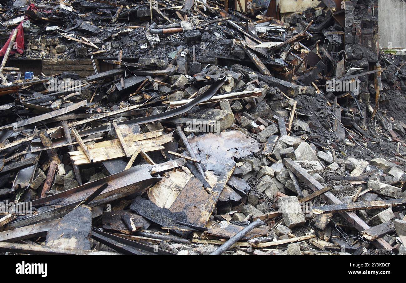Black burned timbers and walls in a collapsed house destroyed by fire ...