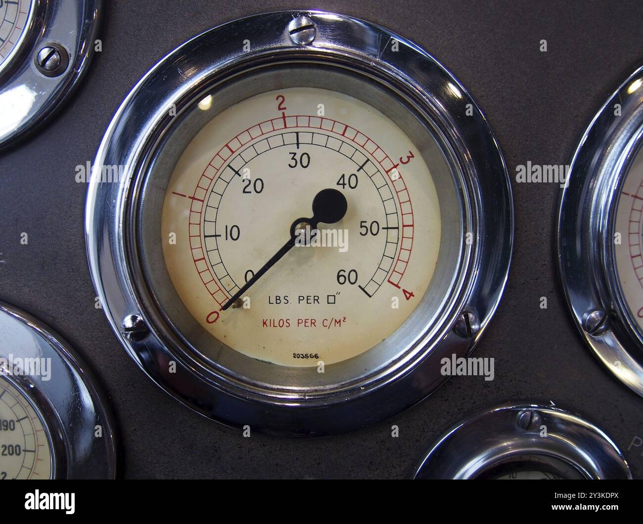 A round metal pressure gauge with a shiny chrome surround on a control ...