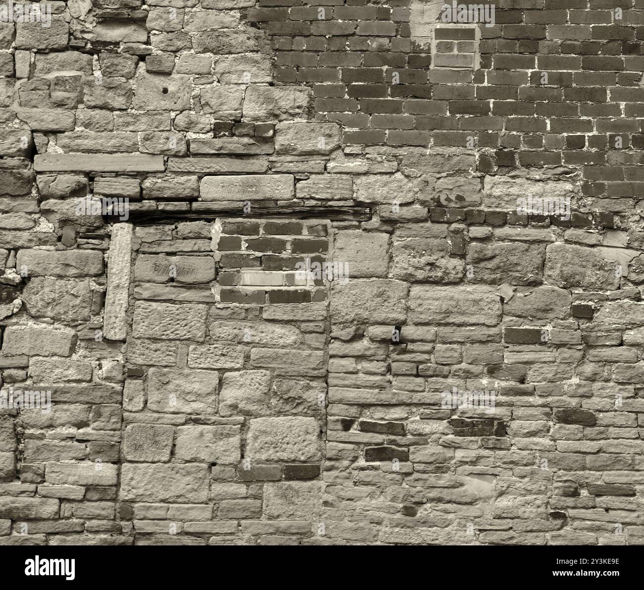 Monochrome sepia toned image of a large old wall made of mixed bricks ...