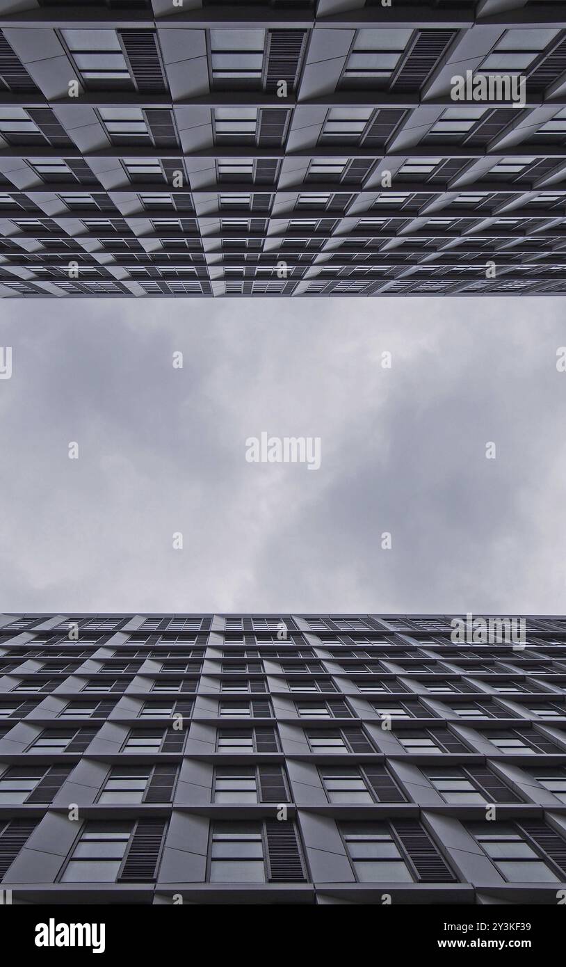 Cloudy sky between two tall modern apartment buildings with repeating ...