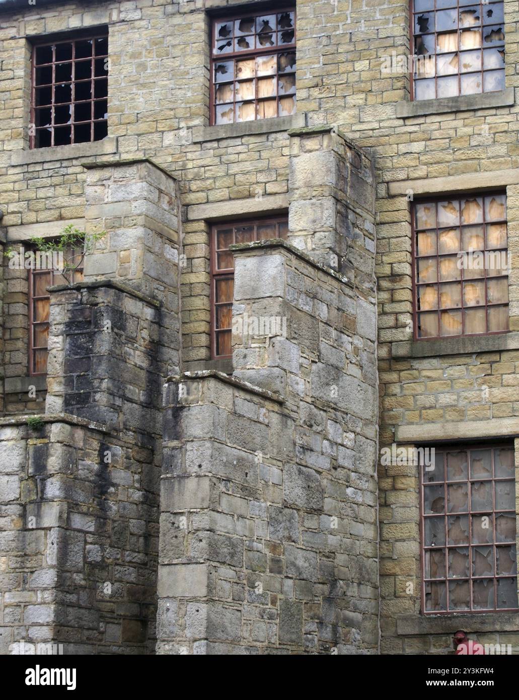 A large decaying old abandoned factory building with boarded up and ...