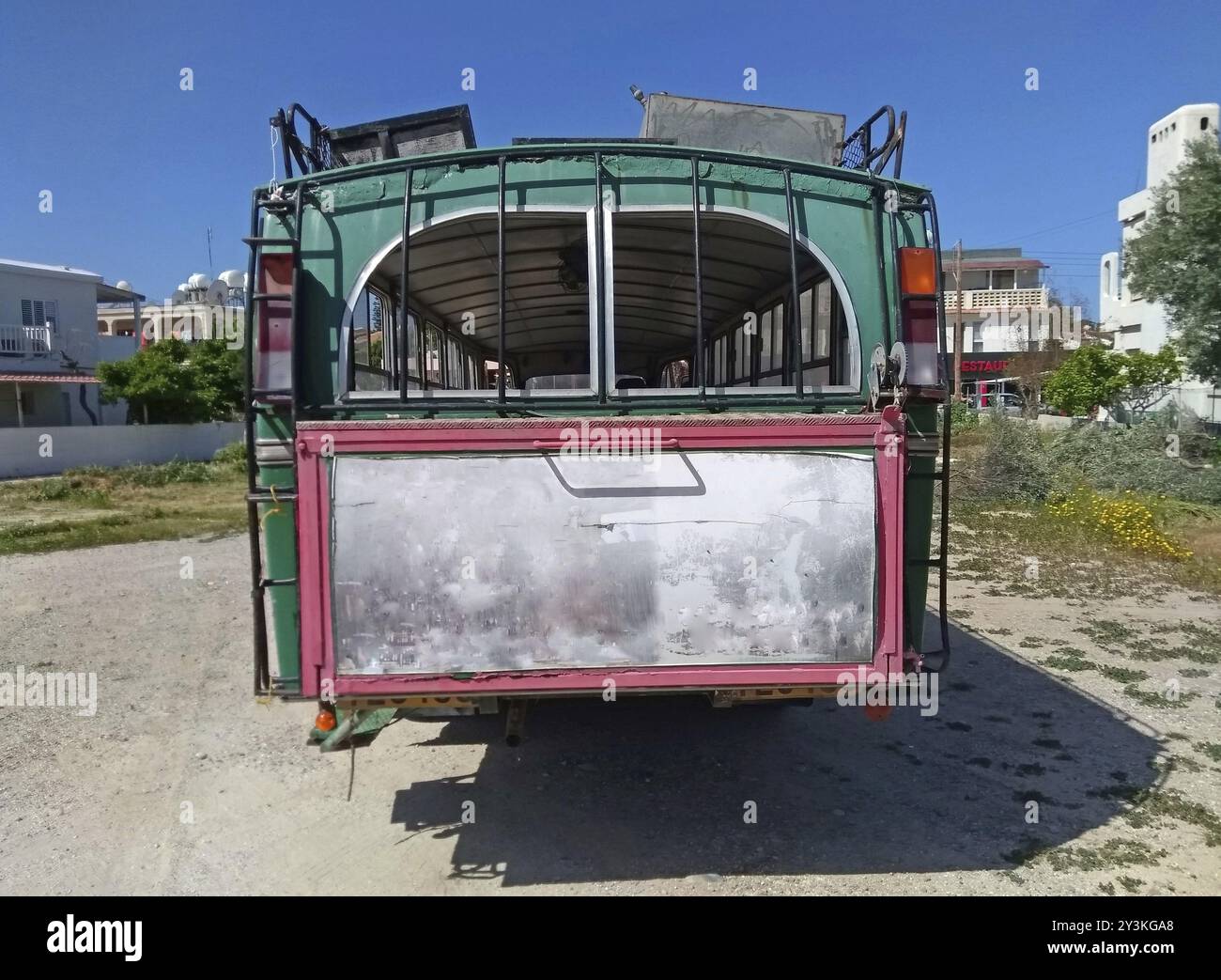 Rear view of an old rusting green painted bus with roof rack parked in ...