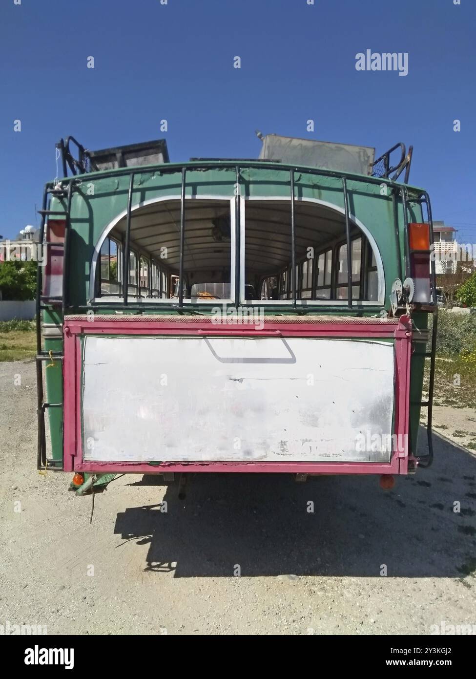 Rear view of an old rusting green painted bus with roof rack parked in ...