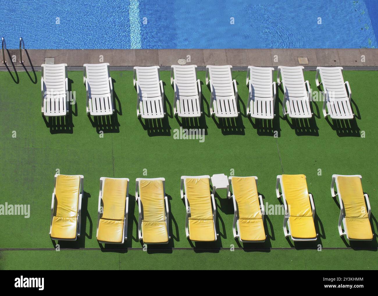 Aerial view of sun loungers on a green background next to a blue ...
