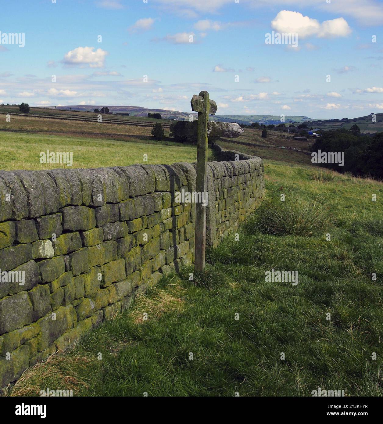 Open countryside with direction sign next to a dry stone wall with ...