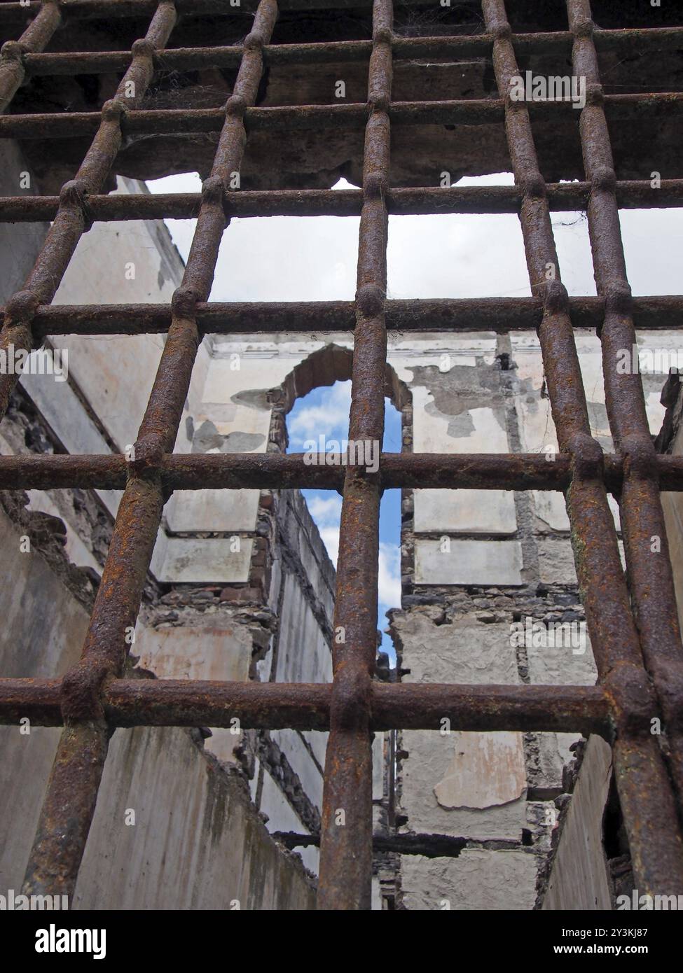 View through rusty iron bars on a window of a ruined collapsing ...