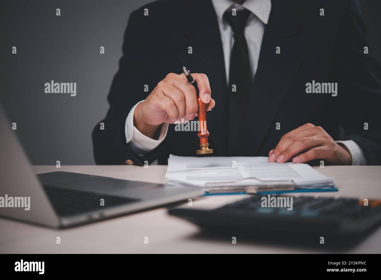 businessman in a suit stamping documents at a desk. Hand holding stamp ...