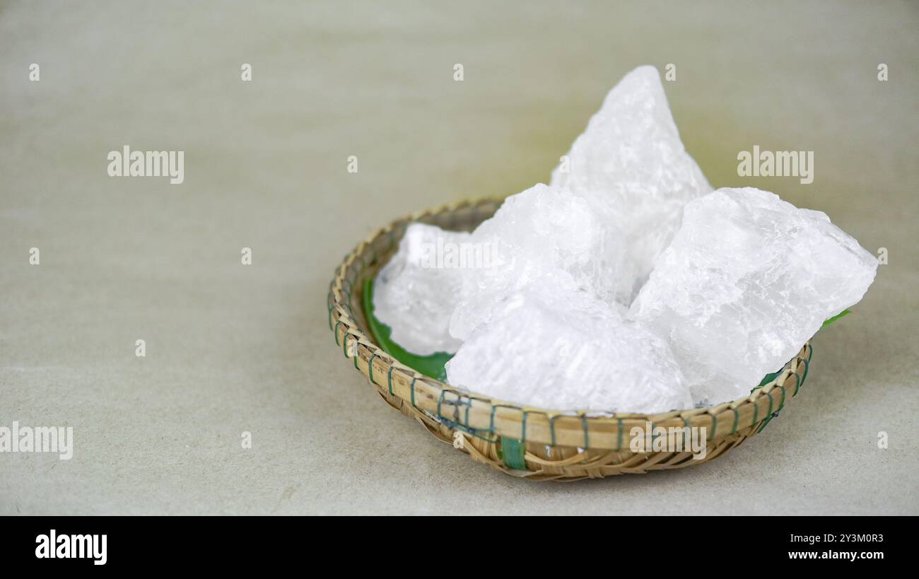 White crystal clear alum cube on brown background. The chemical ...