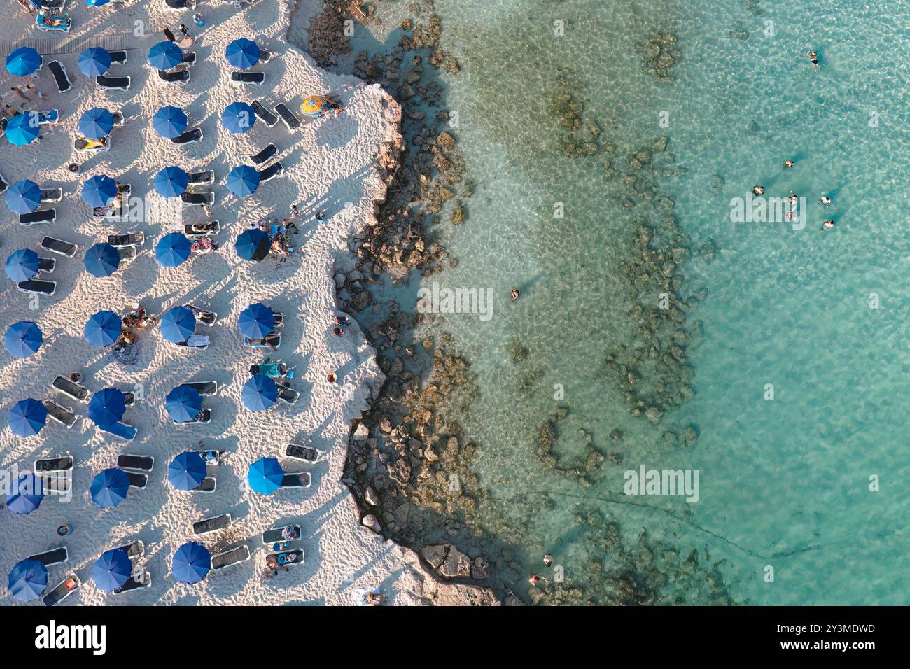 Aerial view of a crowded beach with tourists relaxing on sunbeds and ...