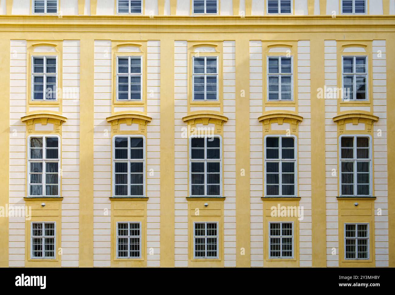 Ornate yellow historic European building facade with barred windows ...