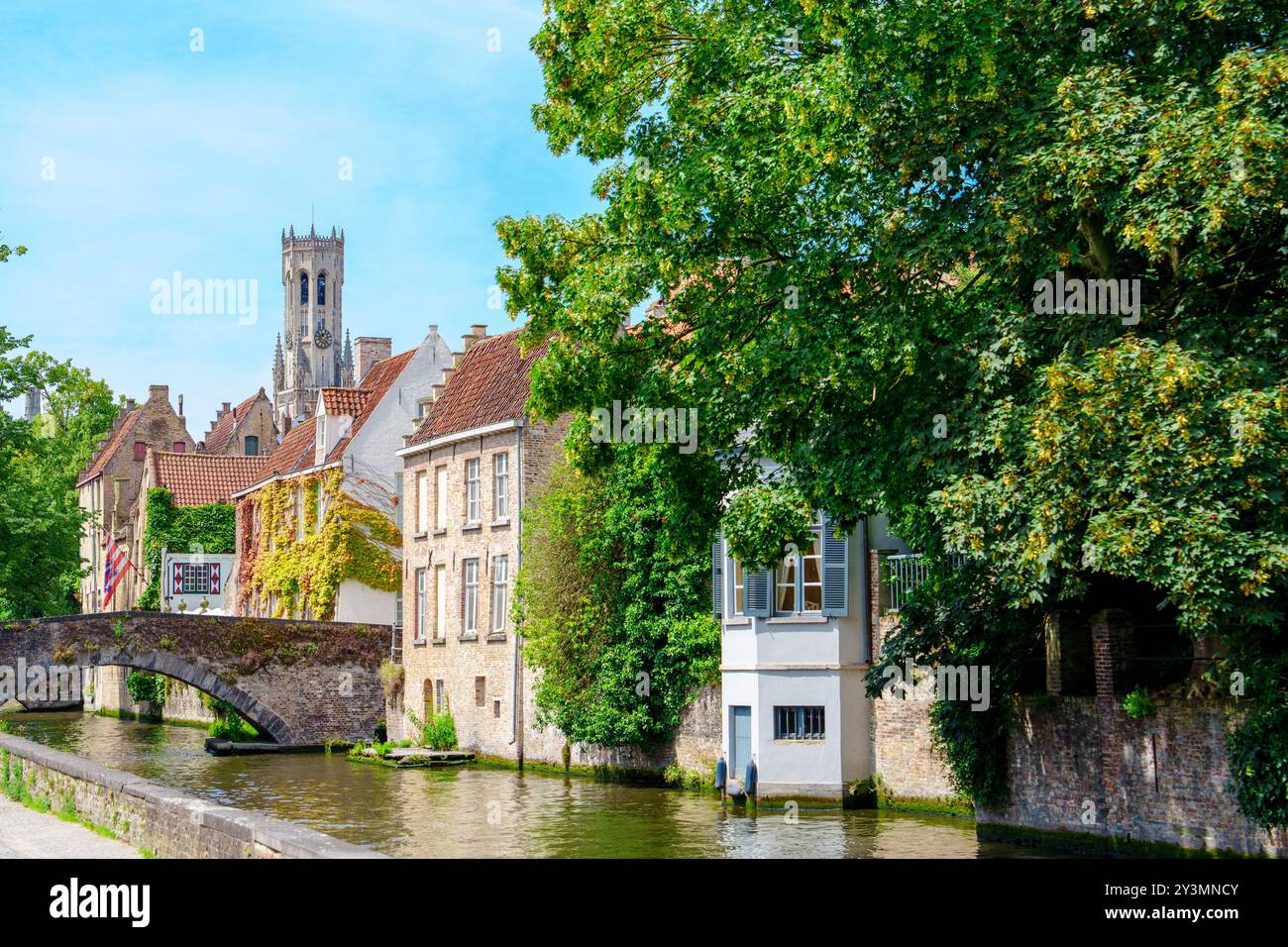Scenic canal with colorful houses and lush trees in Bruges, Belgium ...